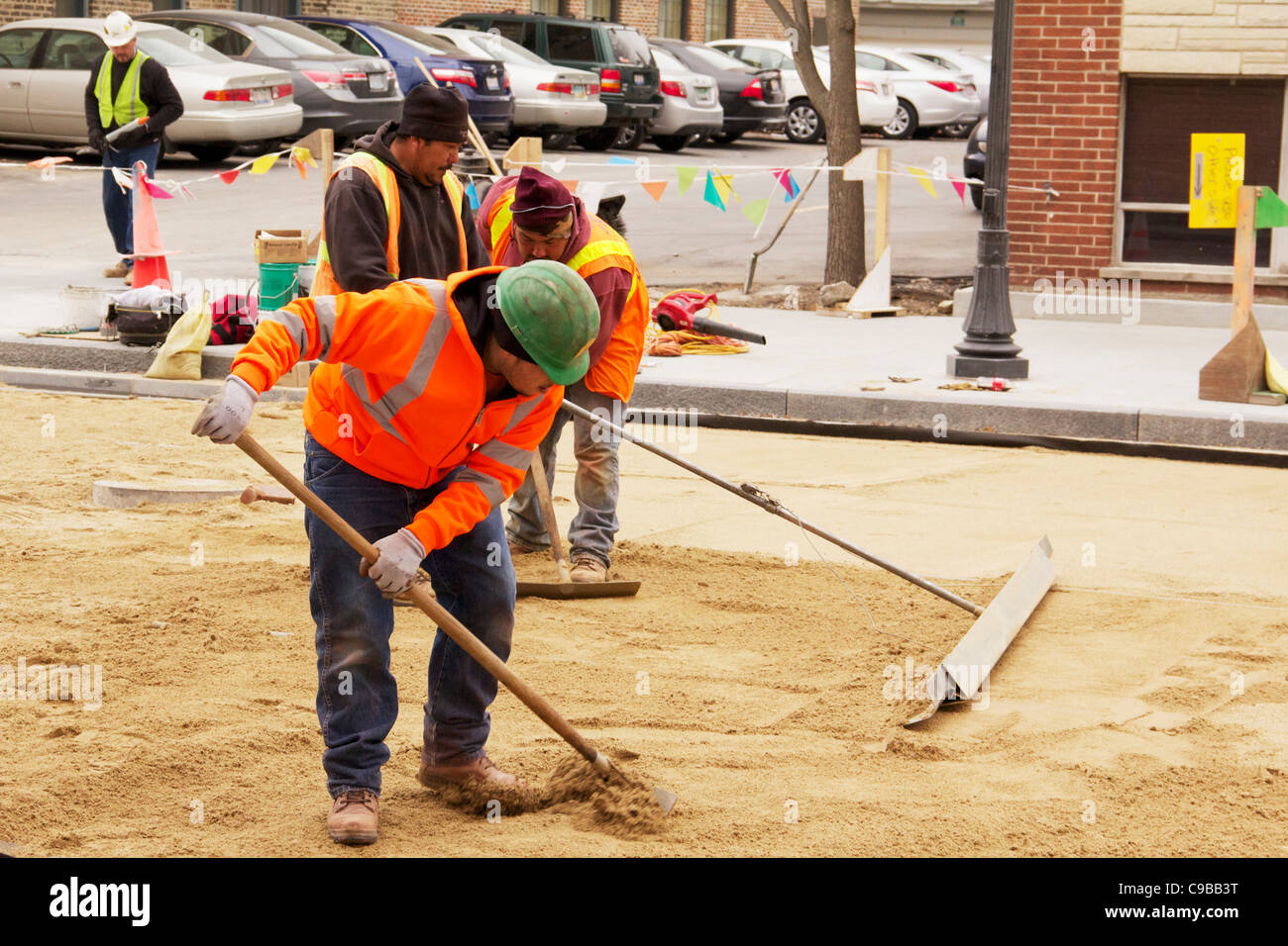 Construction workers prepare sand bed for paving bricks during Marion ...