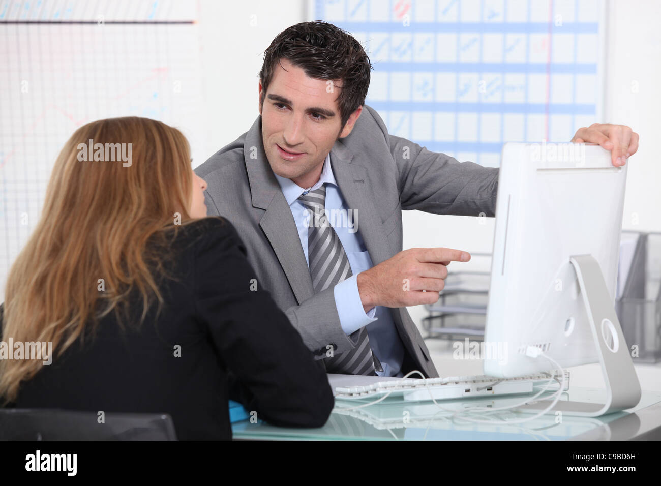 Man showing woman computer screen Stock Photo - Alamy