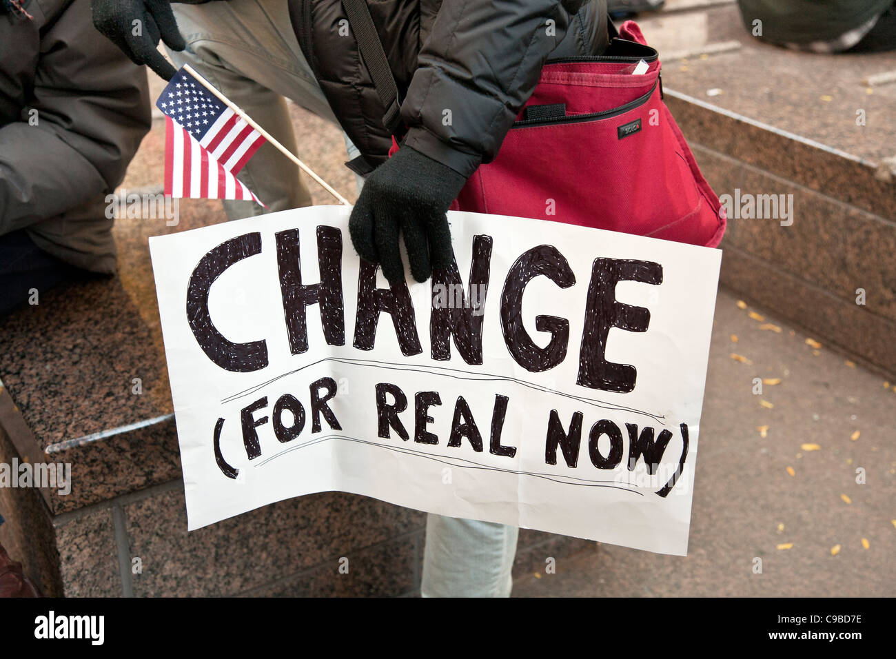 gloved hand holds small American flag & sign advocating change in ...