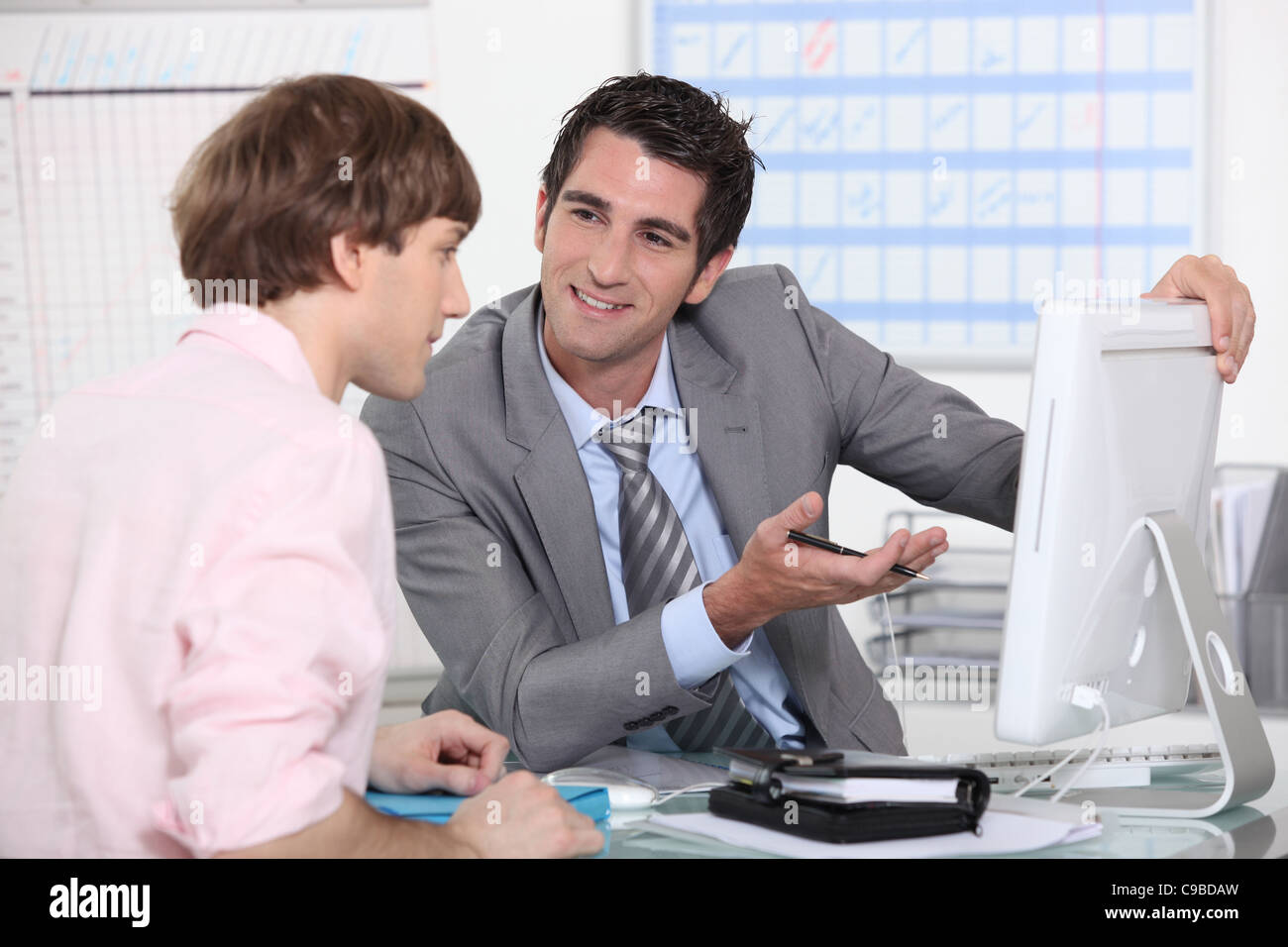 Colleagues looking at computer Stock Photo - Alamy