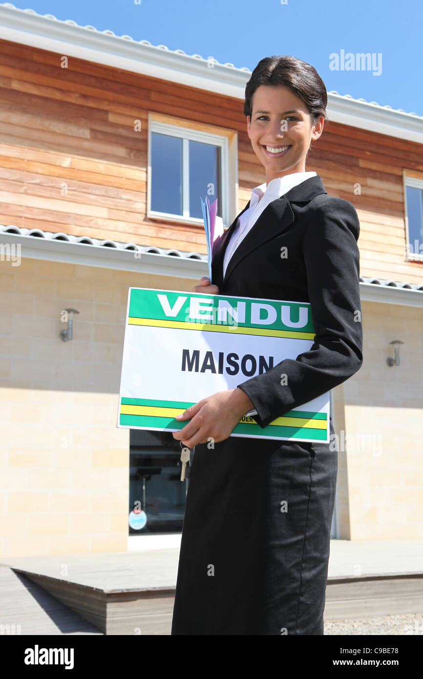 Estate agent with a vendu sign Stock Photo - Alamy
