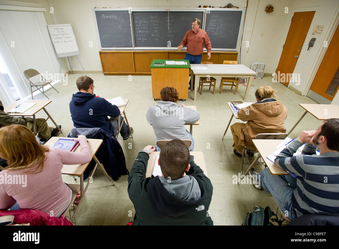 Students at a desk and teacher in the front of a classroom Stock Photo ...