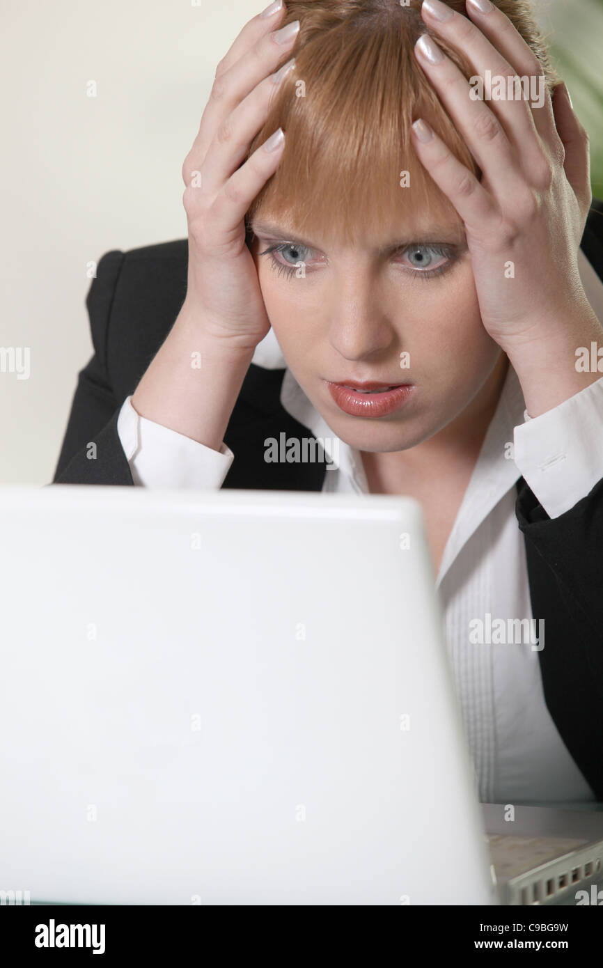 Woman holding her head in shock as she looks at a laptop computer Stock ...