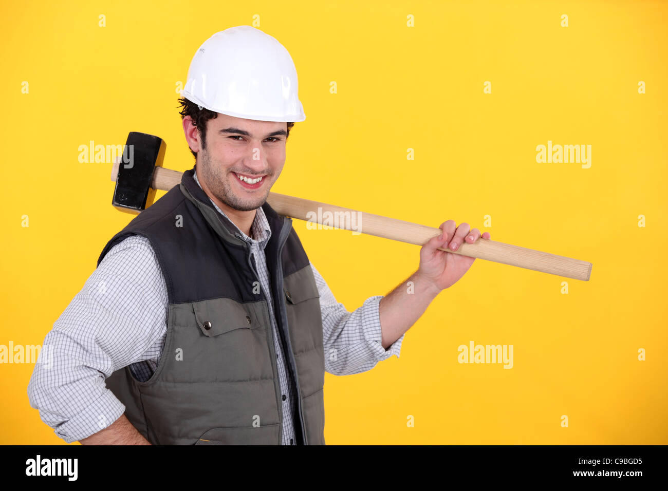 Happy builder carrying sledge-hammer Stock Photo - Alamy