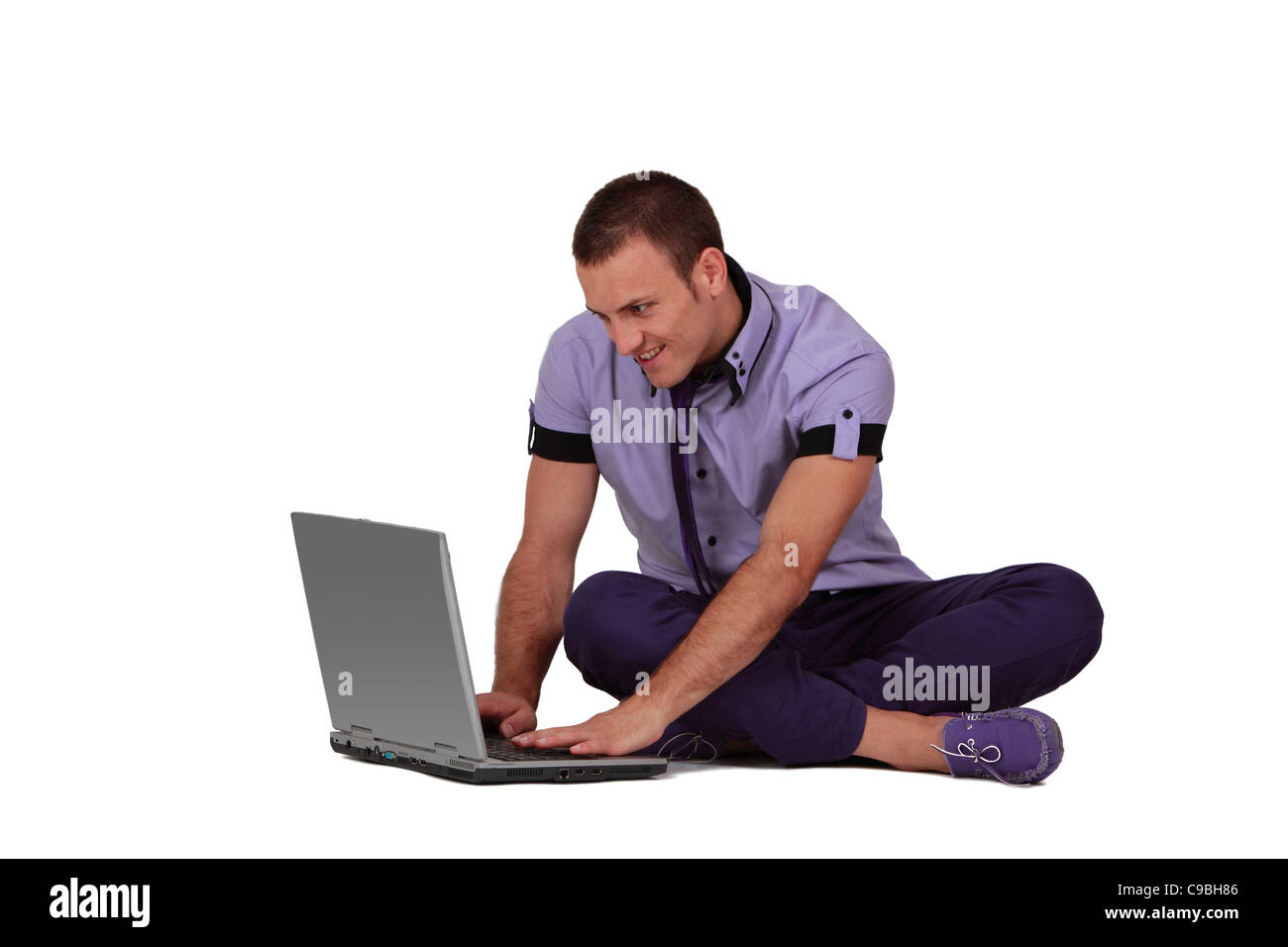 Young man sitting down and working on a laptop isolated aginst a white ...