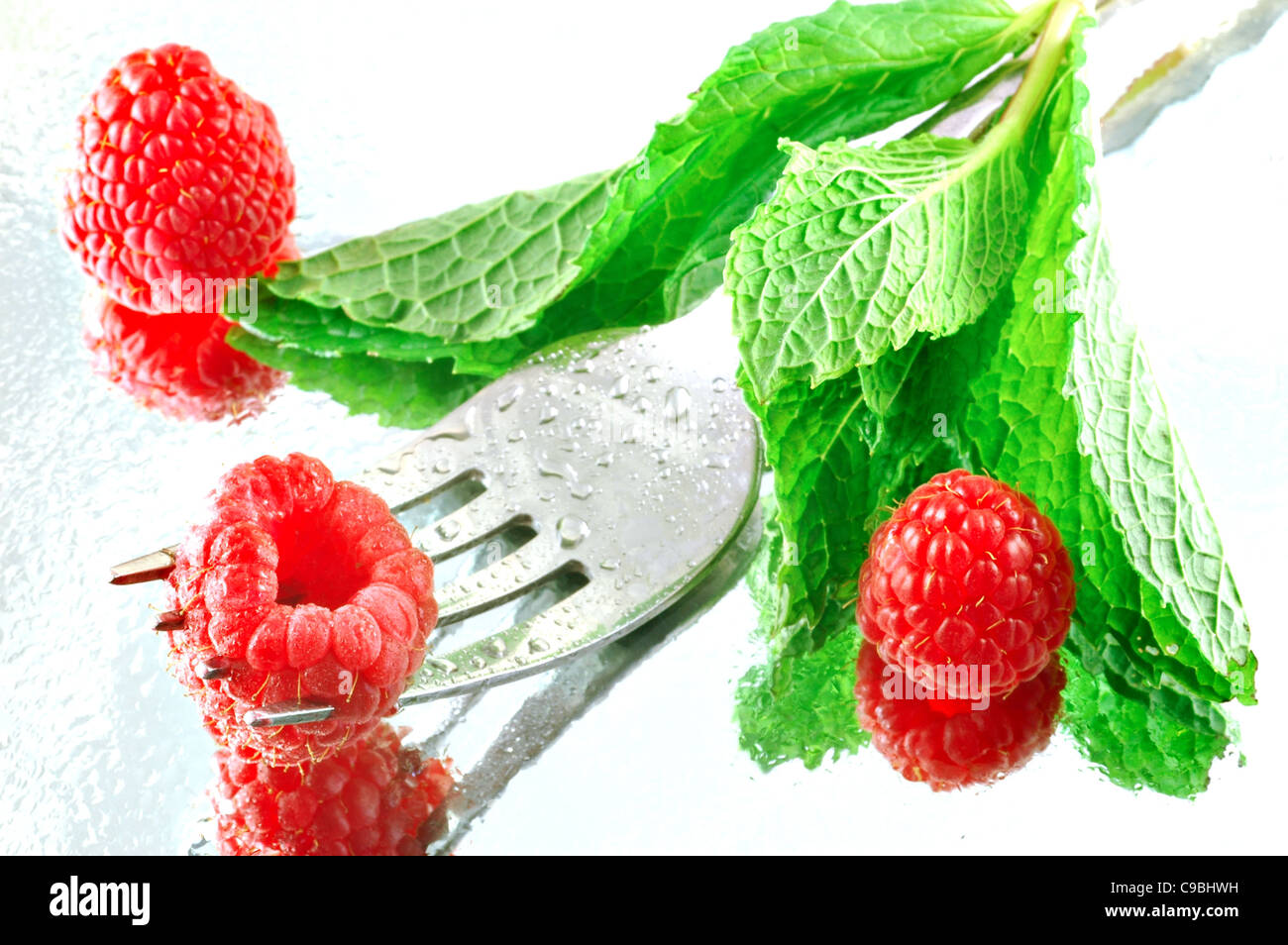 Fresh chilled raspberries with mint on a reflective background with a ...