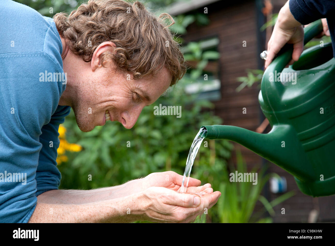 Man holding water poured from watering can Stock Photo - Alamy