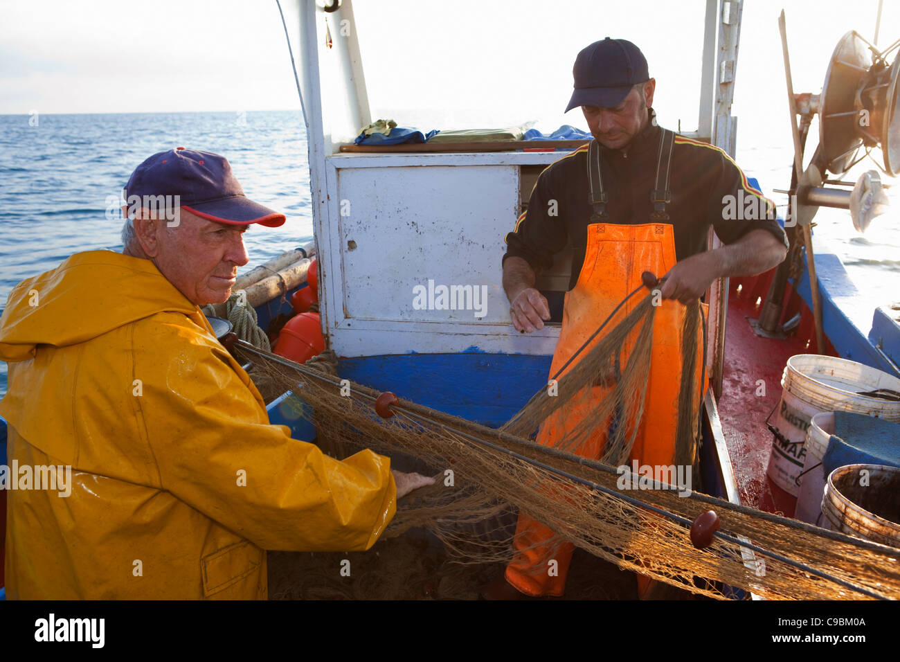 Fishermen reeling in nets on boat Stock Photo - Alamy