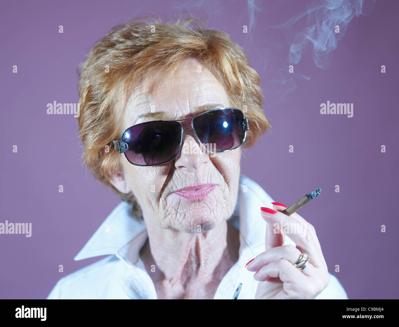Senior woman smoking against purple background Stock Photo - Alamy