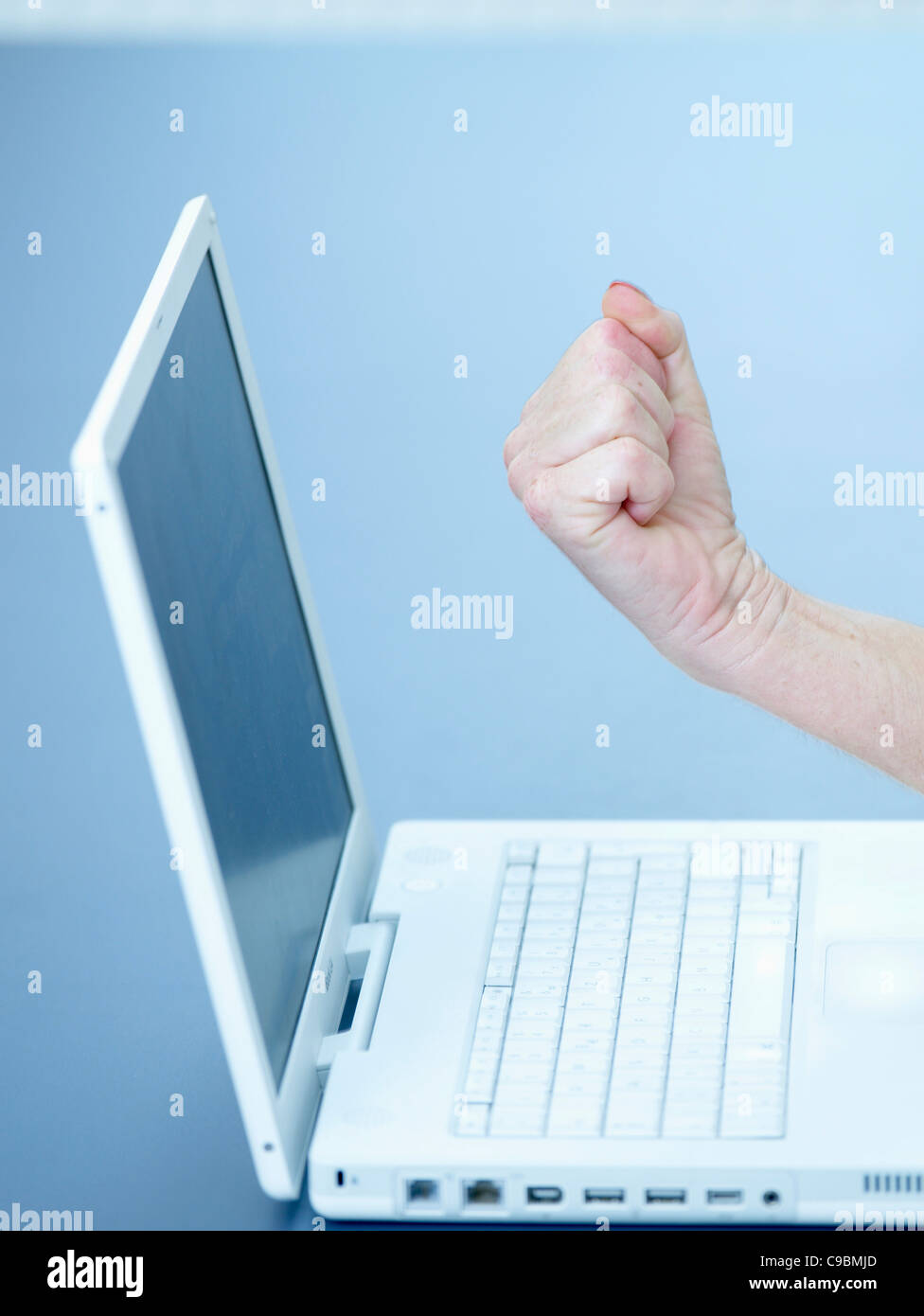 Laptop with human hand showing fist Stock Photo - Alamy