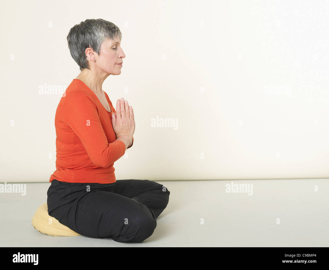 Senior woman sitting in prayer position Stock Photo - Alamy