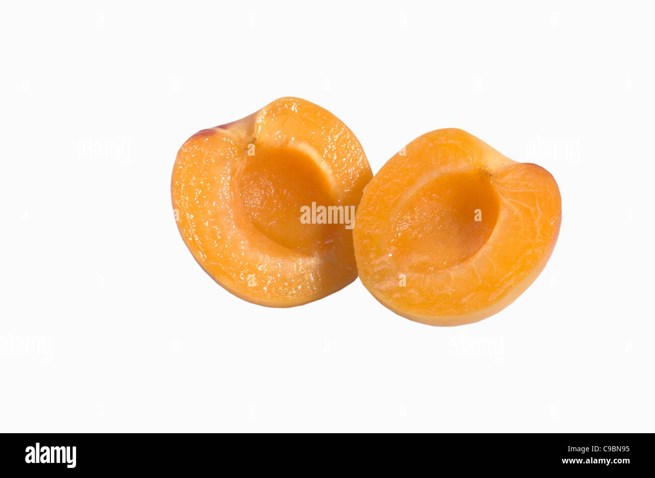Apricots cut in halves against white background Stock Photo - Alamy