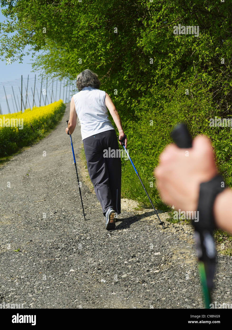 Germany, Bavaria, Mature woman nordic walking with man holding pole ...