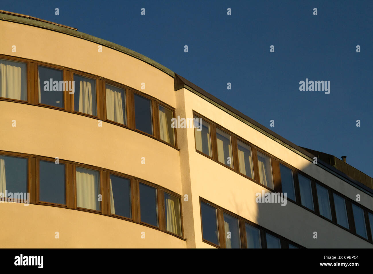 Close photo of curved building with windows and blue sky at sunset ...