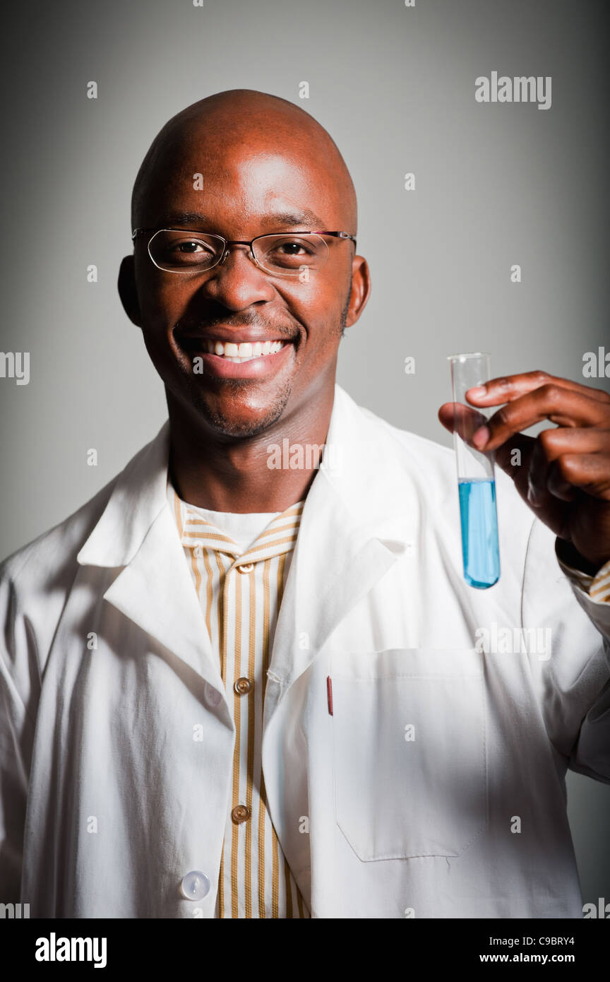 Portrait of male science teacher holding test tube in science classroom ...
