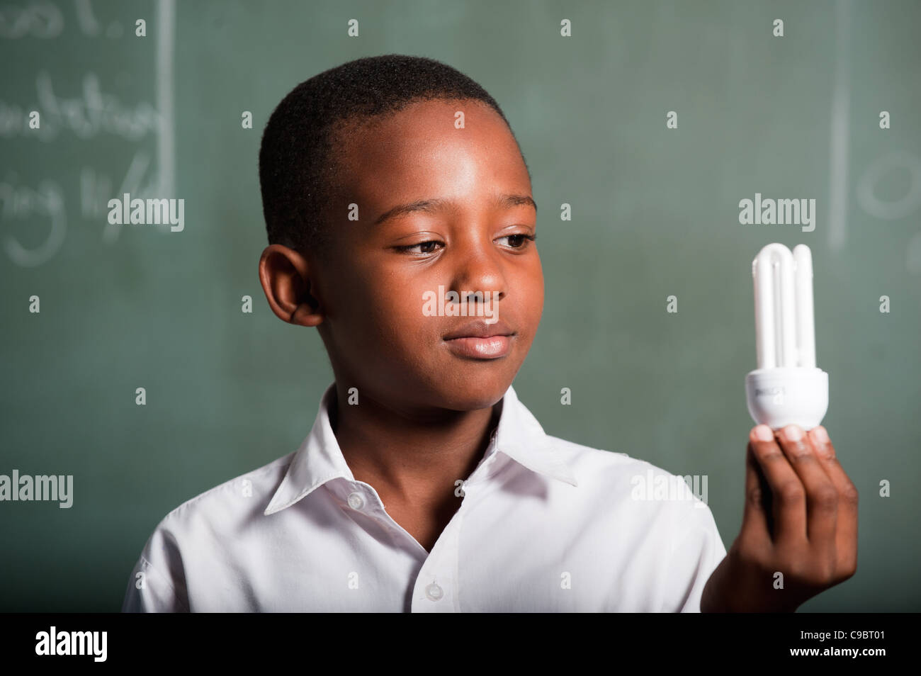 Boy holding energy saving lightbulb in classroom, Johannesburg, Gauteng ...