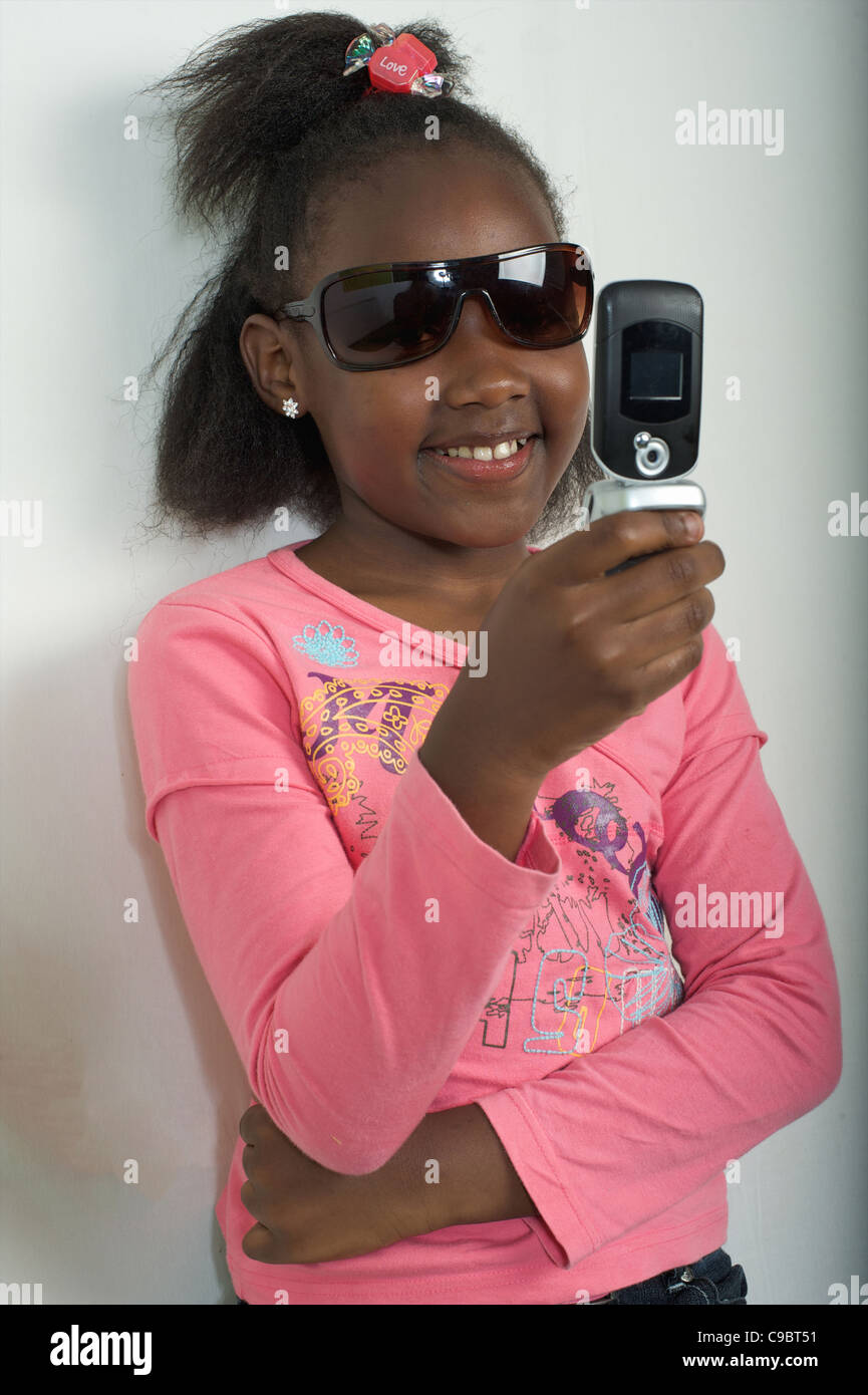 Young Kenyan girl in sunglasses playing with mobile phone, Nairobi ...