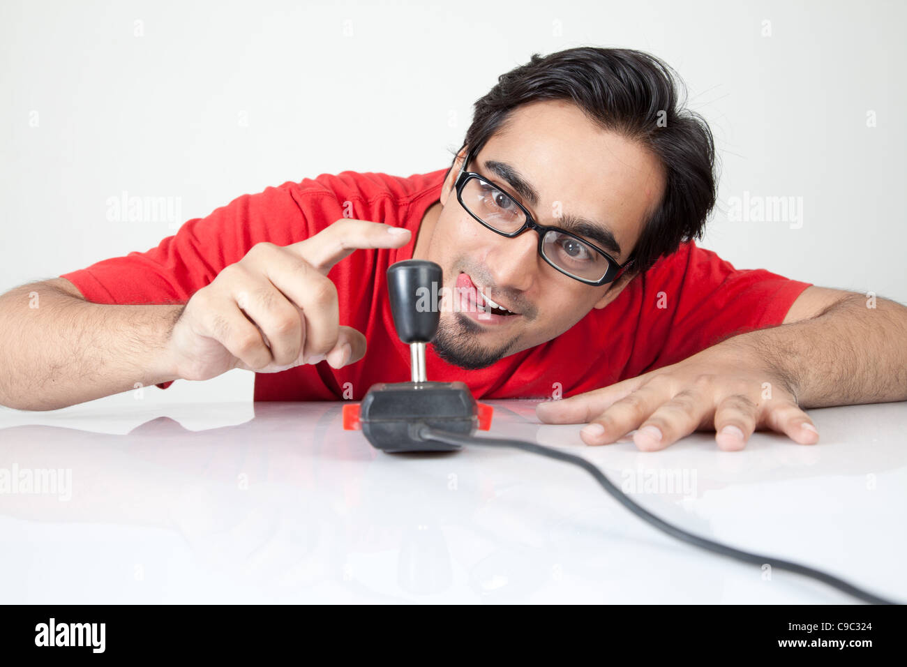 Nerd touching a retro game joystick Stock Photo - Alamy