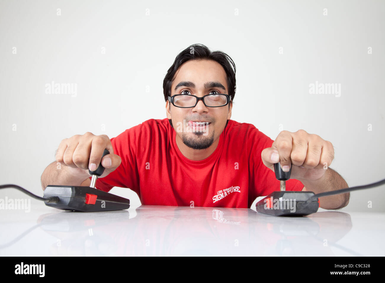 Nerd playing with two retro joystick controllers Stock Photo - Alamy
