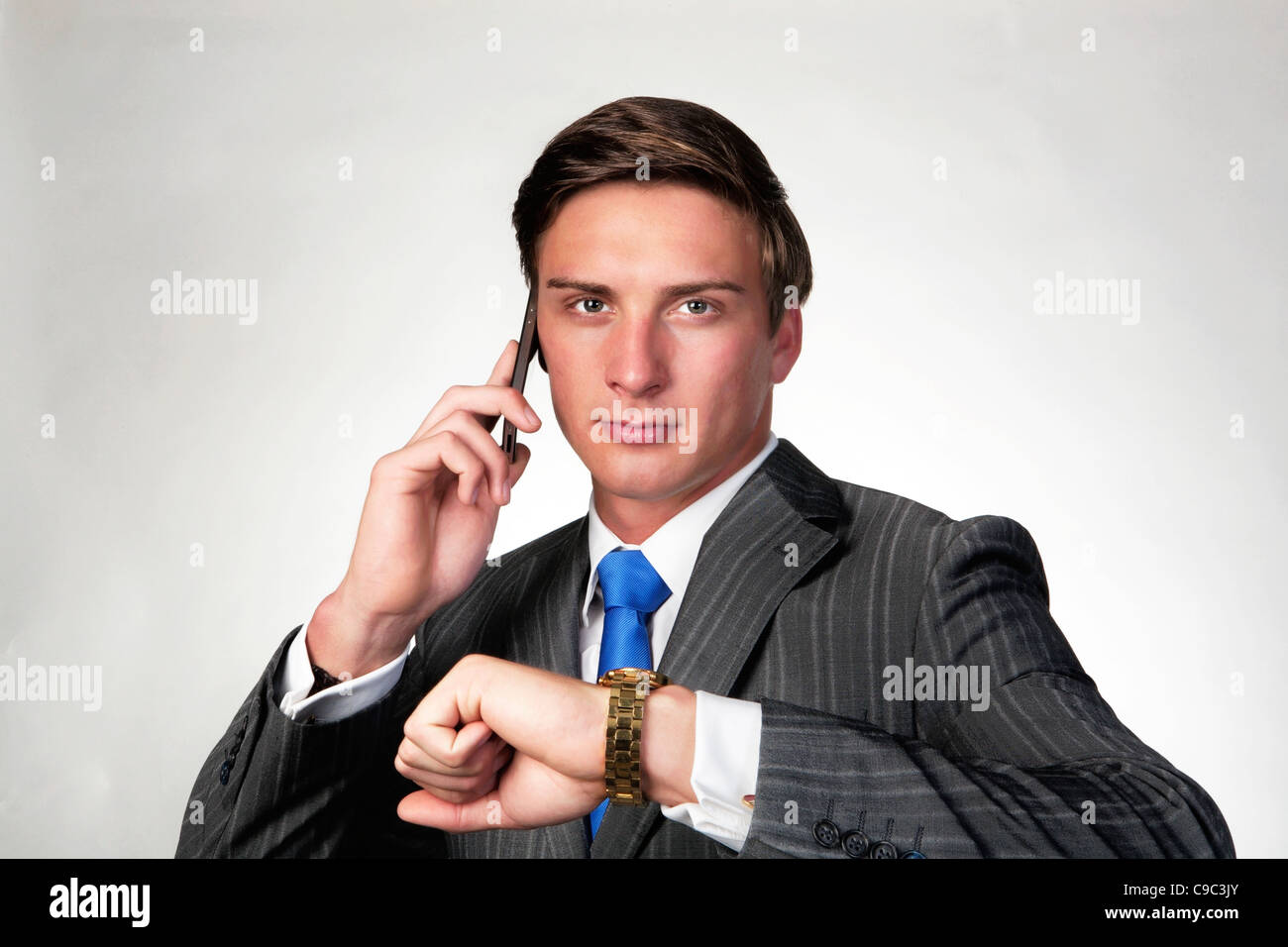 man on his mobile phone looking at his watch Stock Photo - Alamy