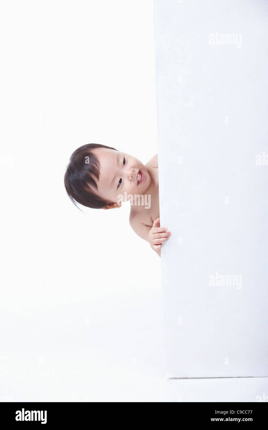 Baby boy peeking from behind a white wall Stock Photo - Alamy
