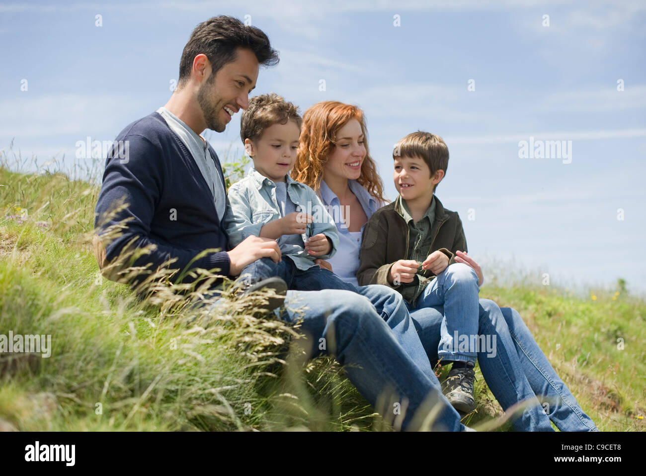 Parents and young boys sitting on meadow Stock Photo - Alamy