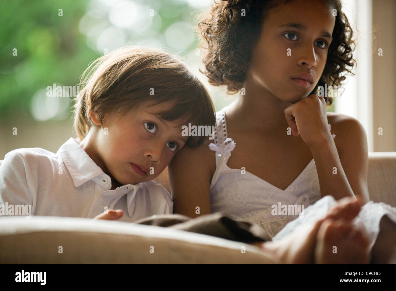 Children watching TV together, boy resting head on sister's shoulder ...