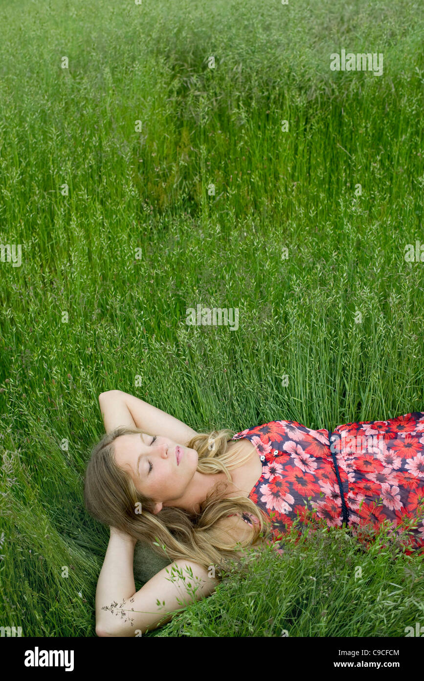 Young woman napping in tall grass Stock Photo - Alamy
