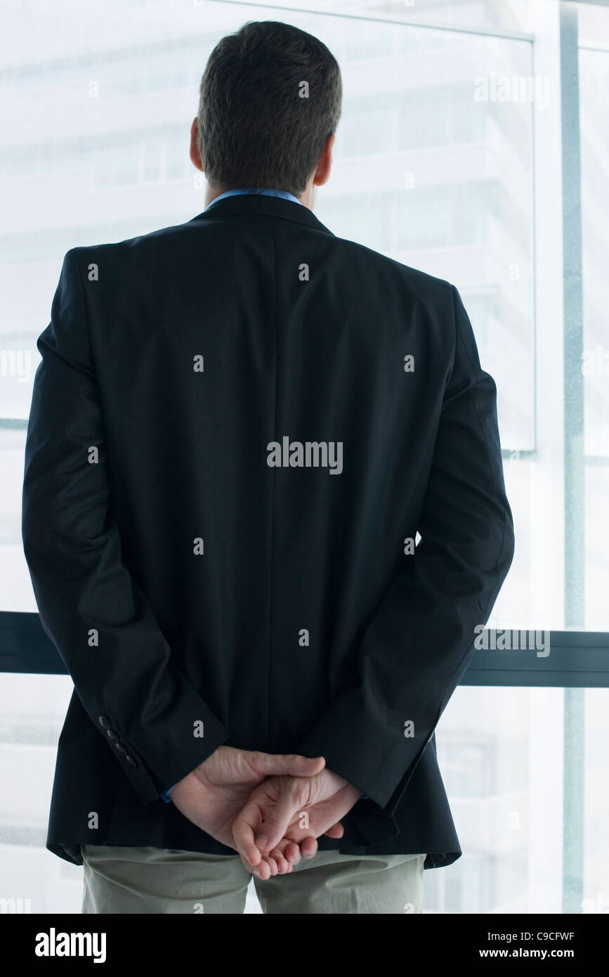 Executive looking out window, rear view Stock Photo - Alamy