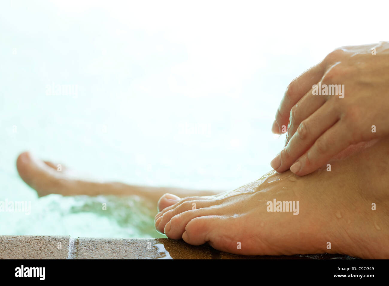Sitting poolside, one foot in water Stock Photo - Alamy