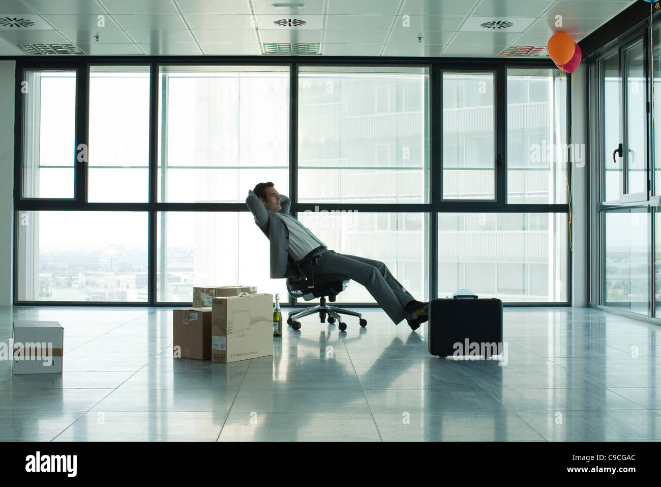 Businessman sitting in empty office with boxes on floor Stock Photo - Alamy