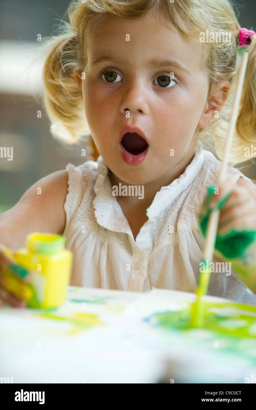 Little girl painting with surprised expression on face Stock Photo - Alamy