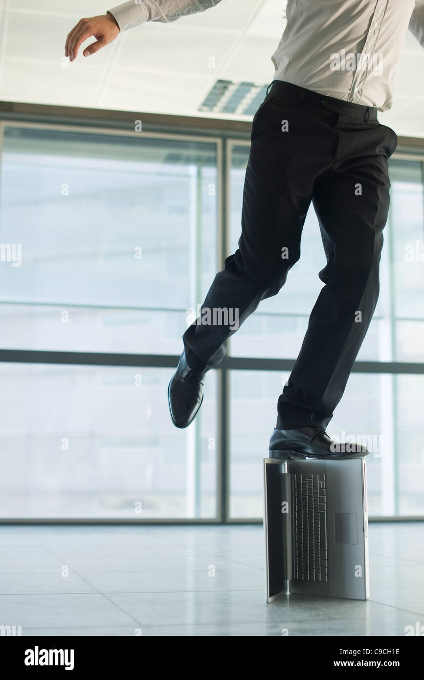 Man standing on top of laptop computer, low angle view Stock Photo - Alamy