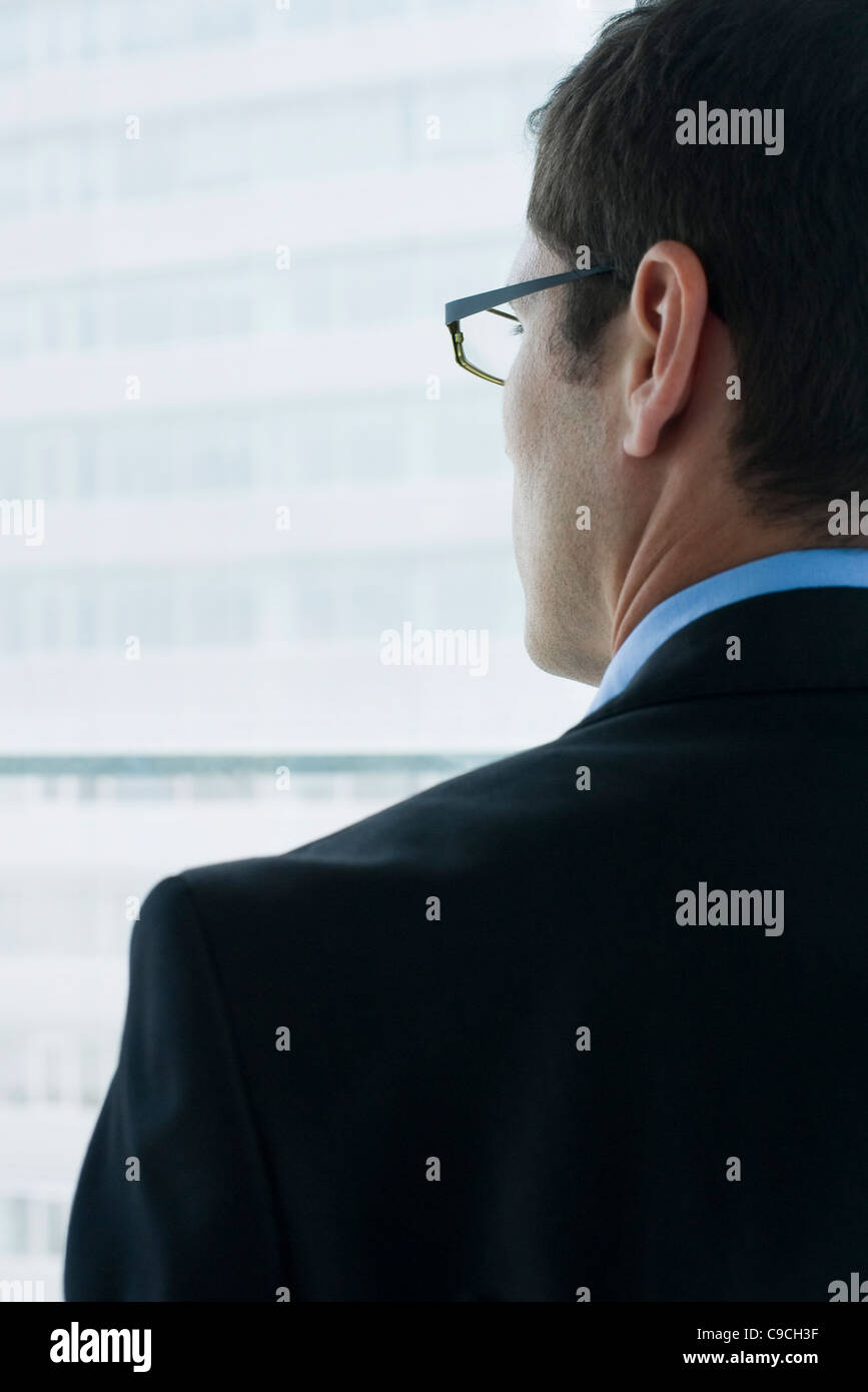 Executive looking out window, rear view Stock Photo - Alamy