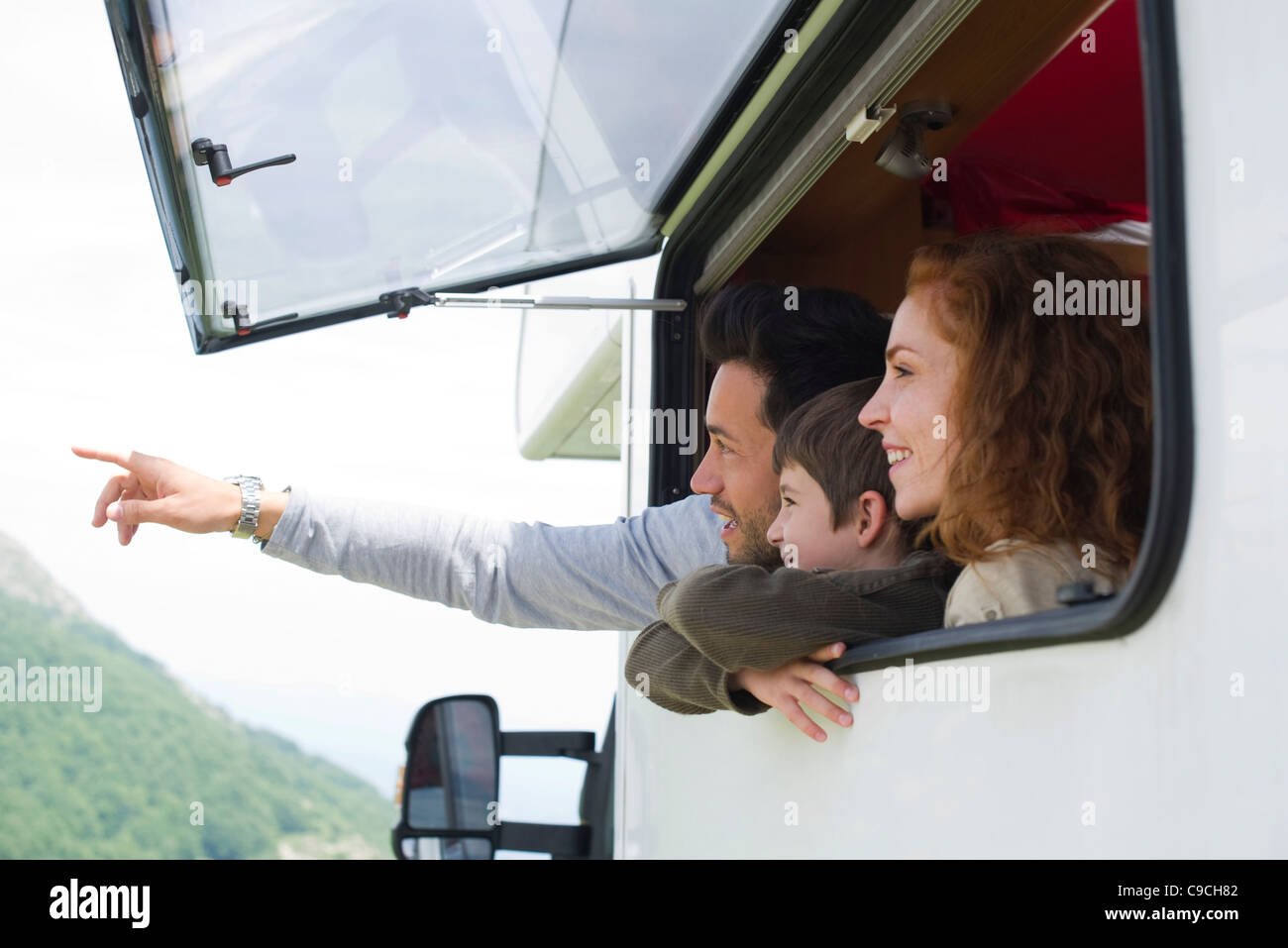 Parents with young son in motor home, father pointing into distance ...