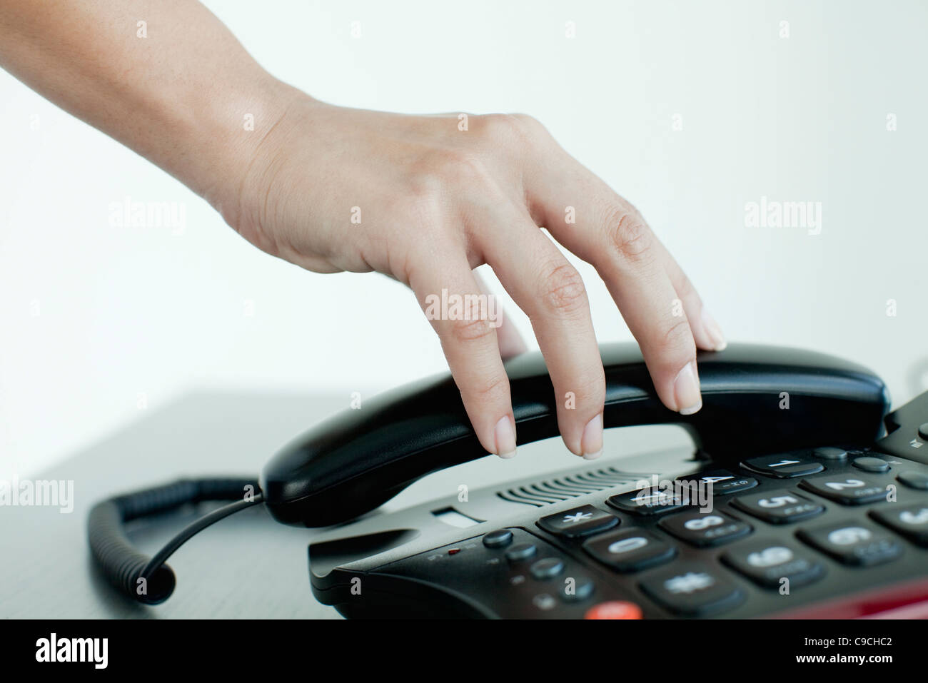 Hand picking up telephone receiver, cropped Stock Photo - Alamy