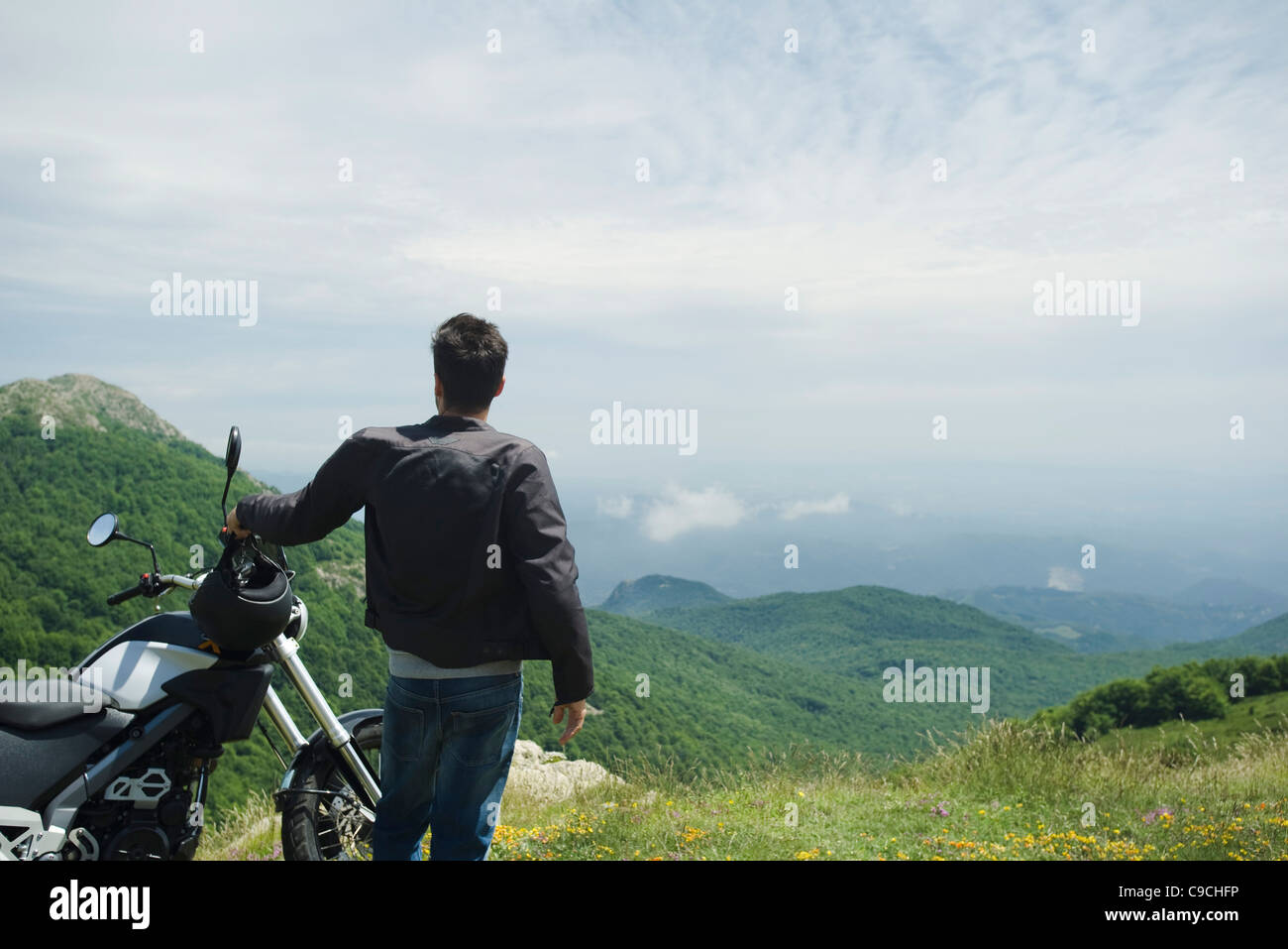 Man standing by motorcycle on mountain, rear view Stock Photo - Alamy