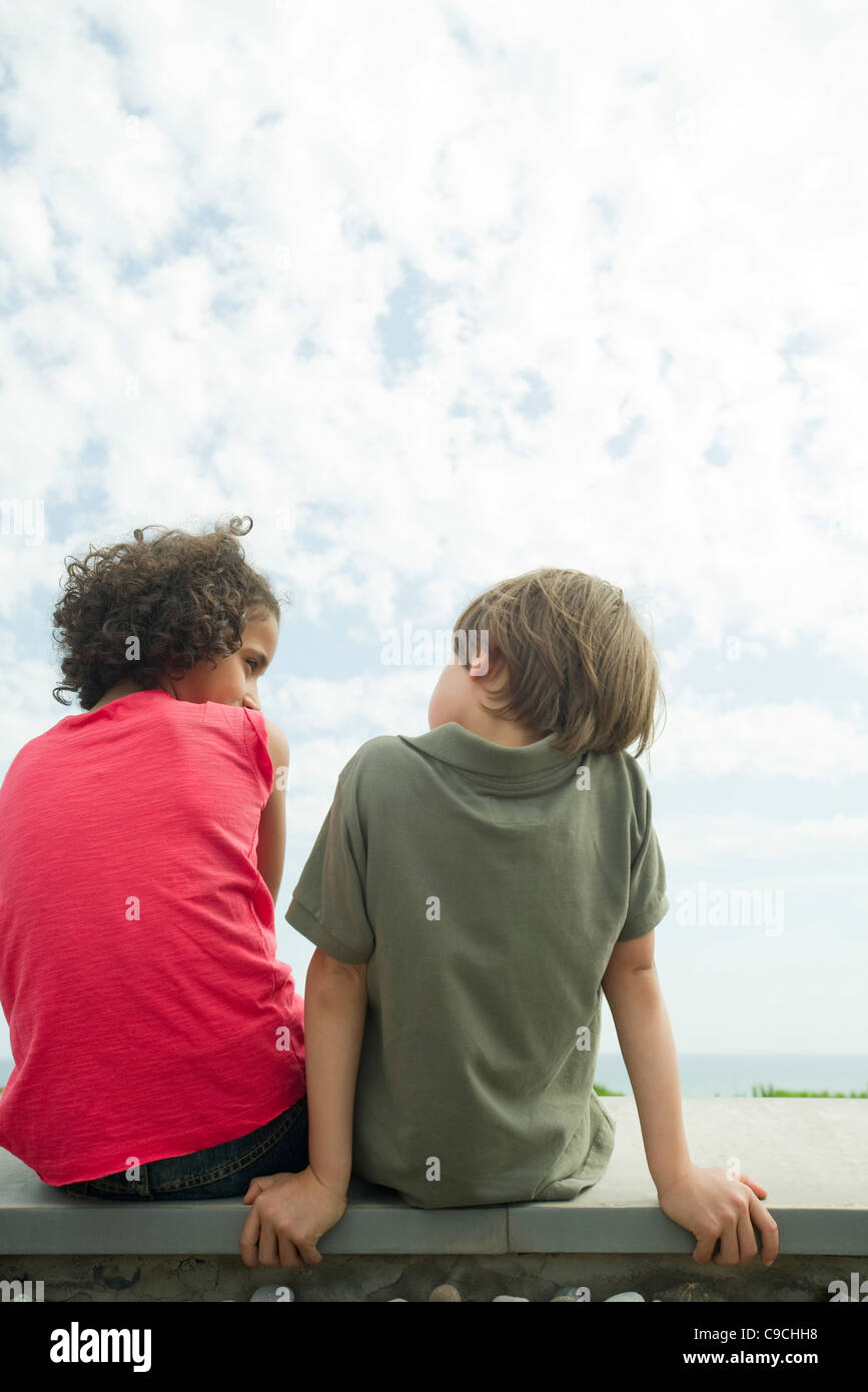 Girl and boy sitting side by side, rear view Stock Photo - Alamy