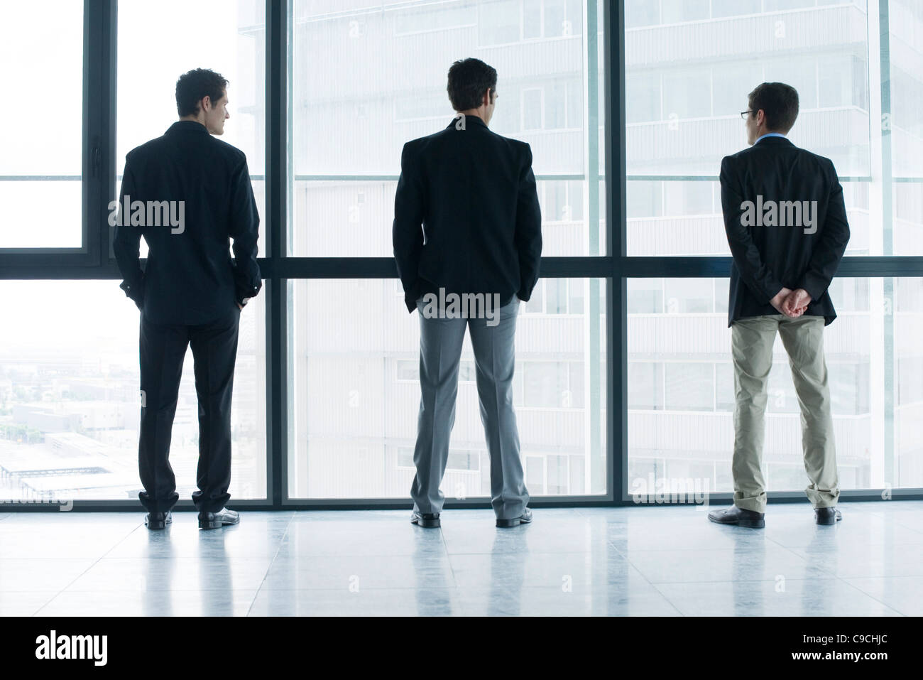 Executives standing side by side, looking out window Stock Photo - Alamy