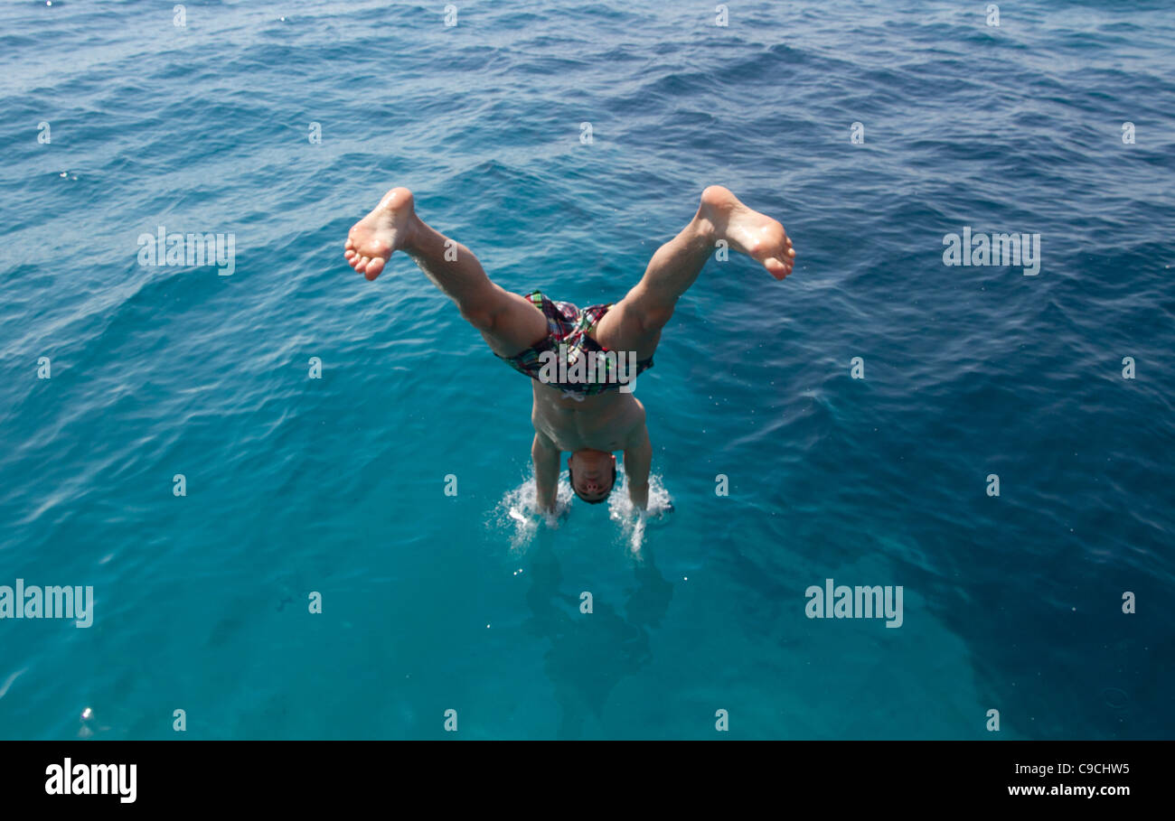 Young man plunges Jumping into the sea water Mallorca Majorca Balearic ...