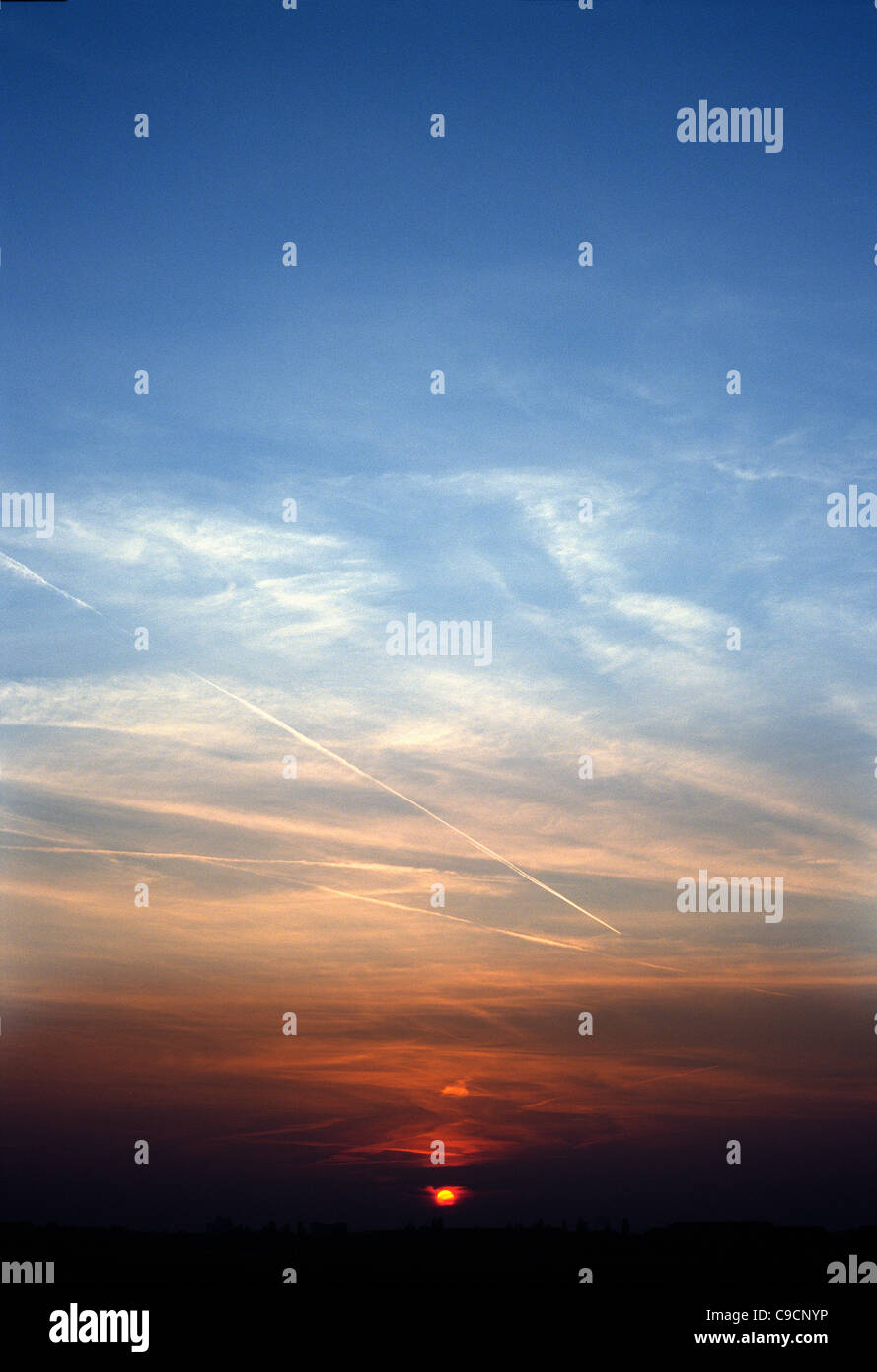Aircraft contrails dissolving into the sunset in the sky above ...