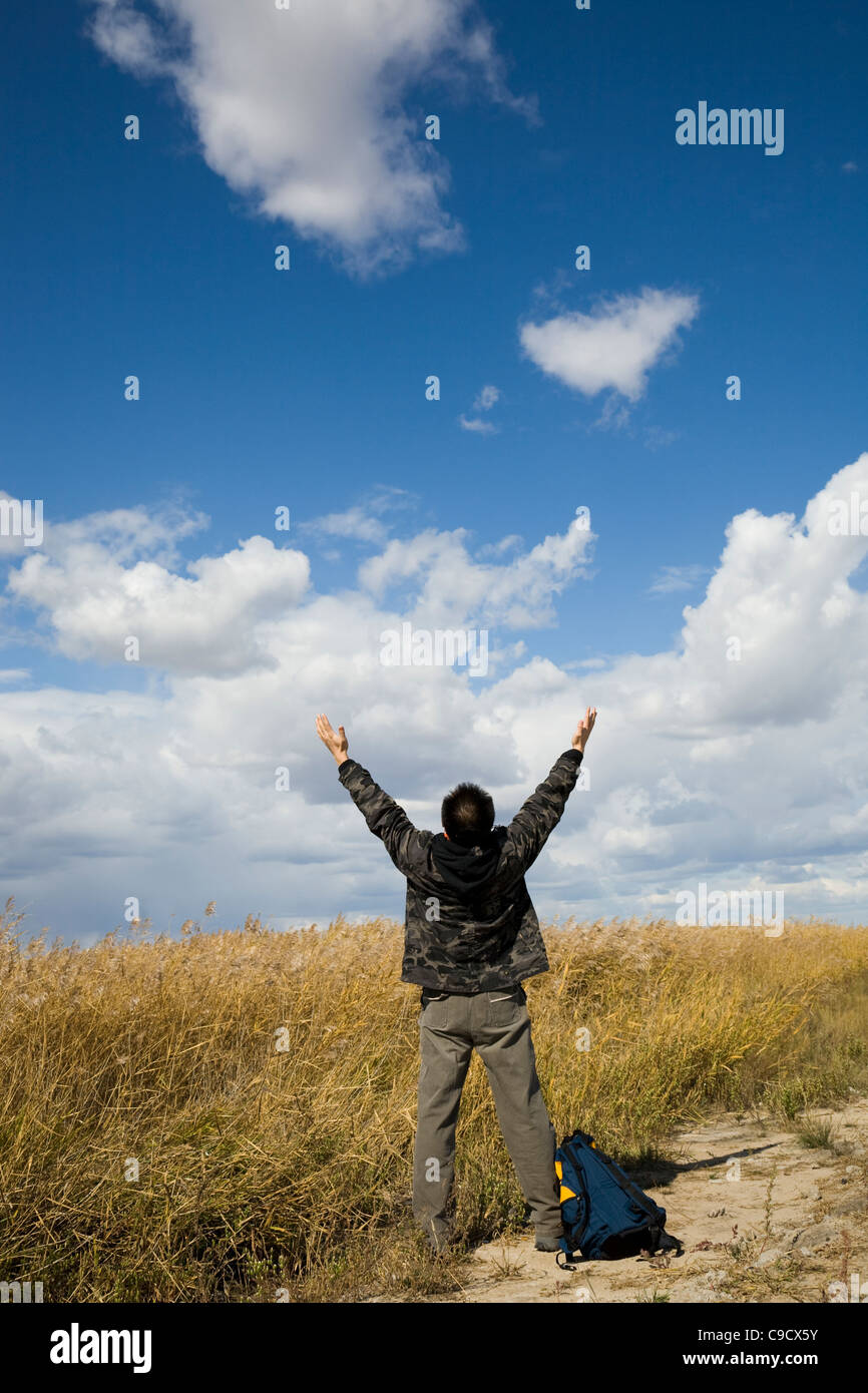 Young man in a grass field raising his hands up to sky Stock Photo - Alamy