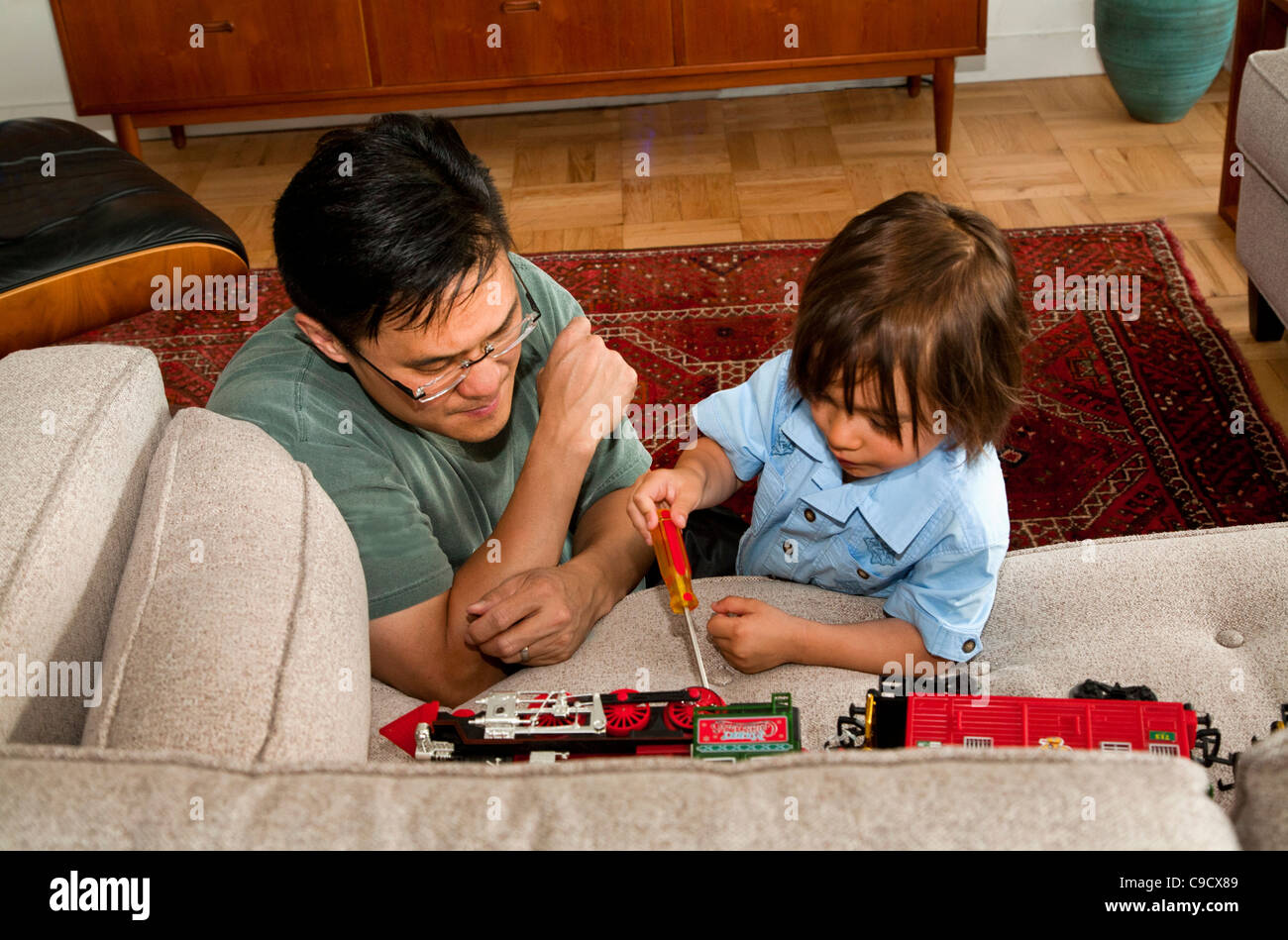 Father and son at home fixing a toy Stock Photo - Alamy
