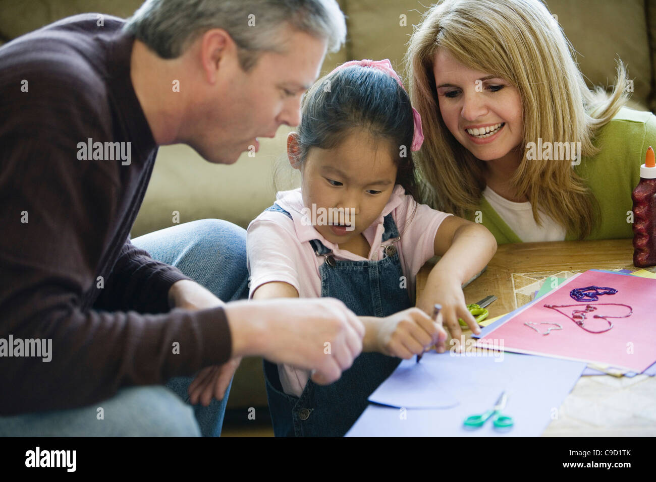 Parents helping their daughter with art work Stock Photo - Alamy