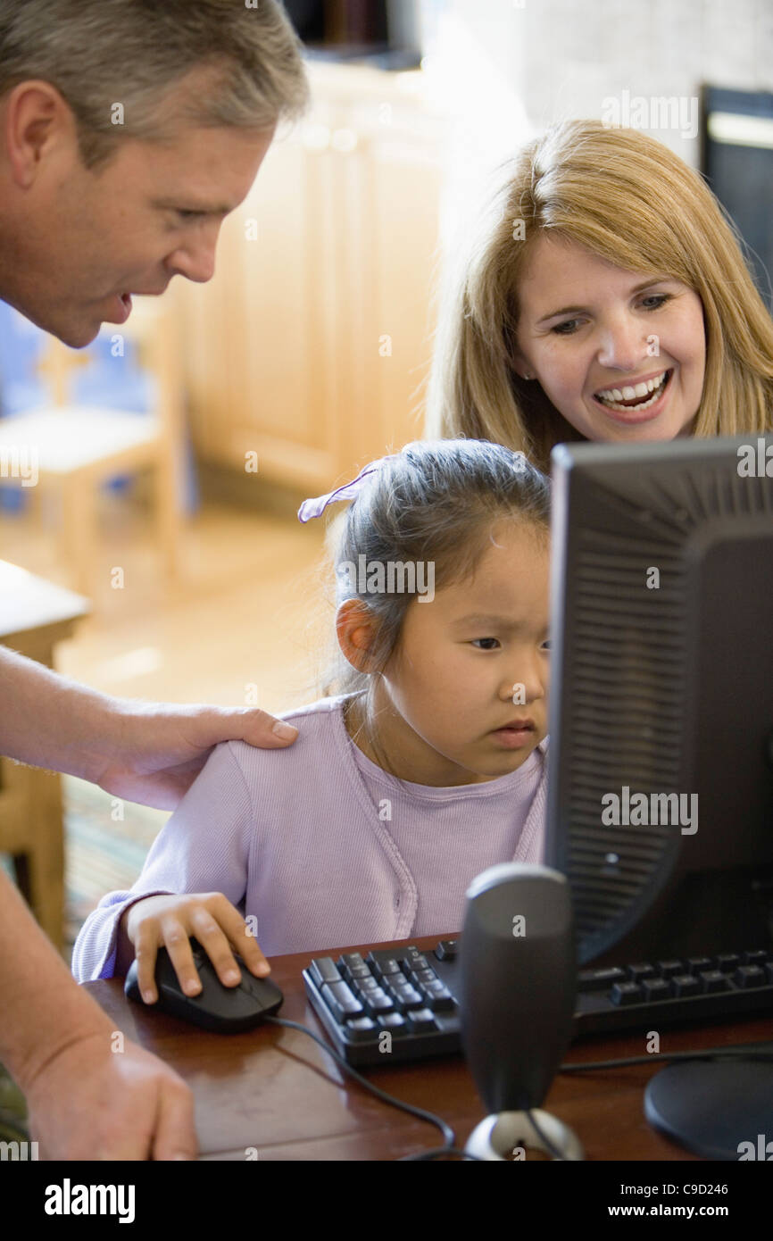 Parents and daughter looking at a computer Stock Photo - Alamy
