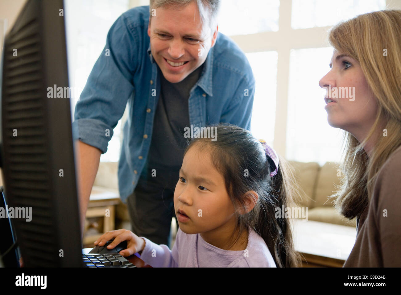 Parents and daughter looking at a computer Stock Photo - Alamy
