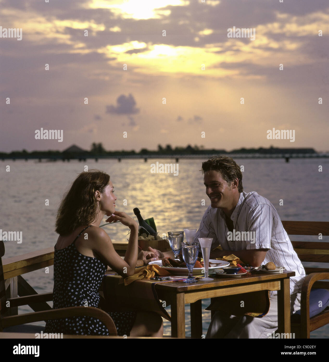 Young couple sitting together at a dining table, Maldives Stock Photo ...