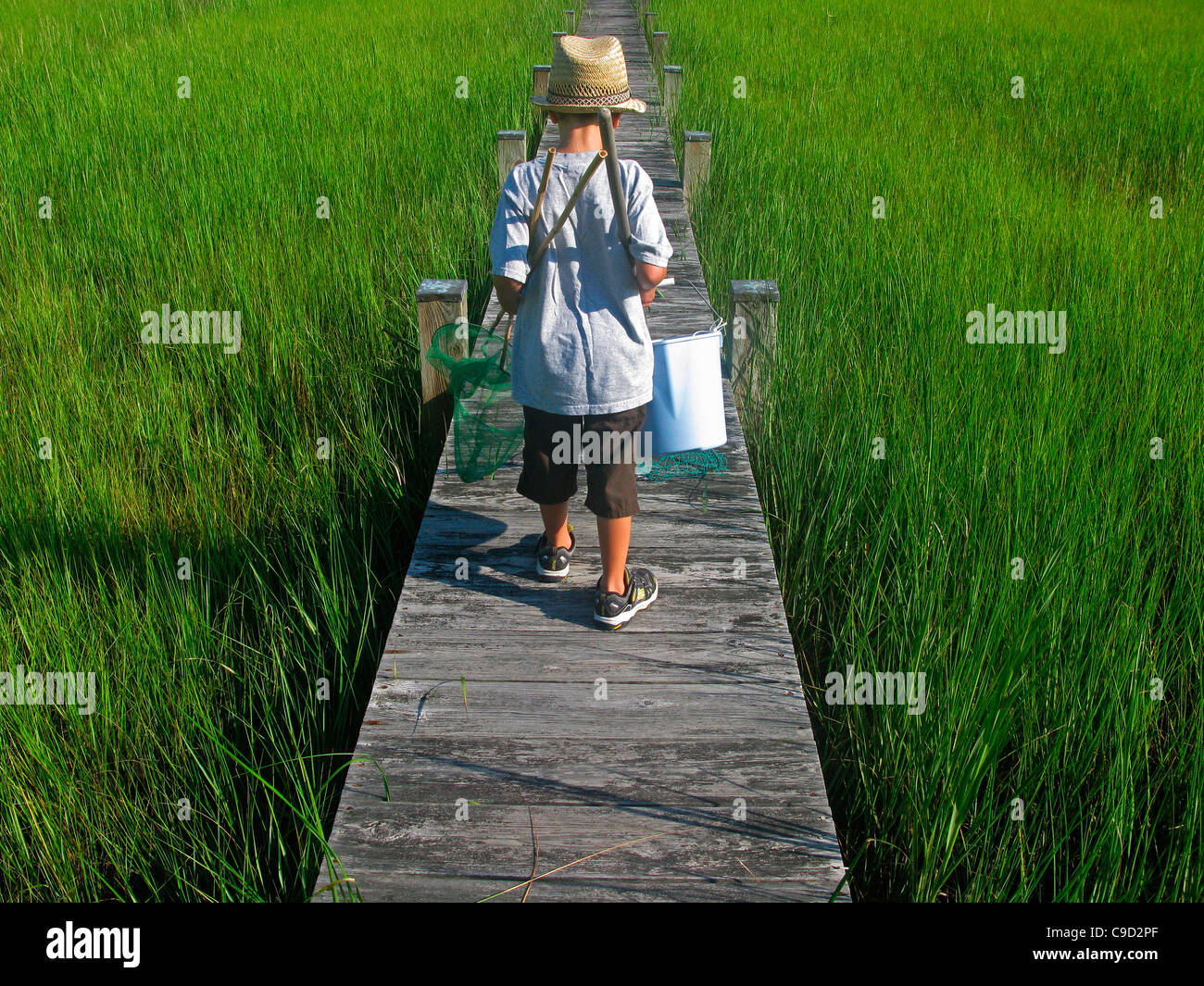 Boy carrying fishing equipment on a boardwalk Stock Photo - Alamy