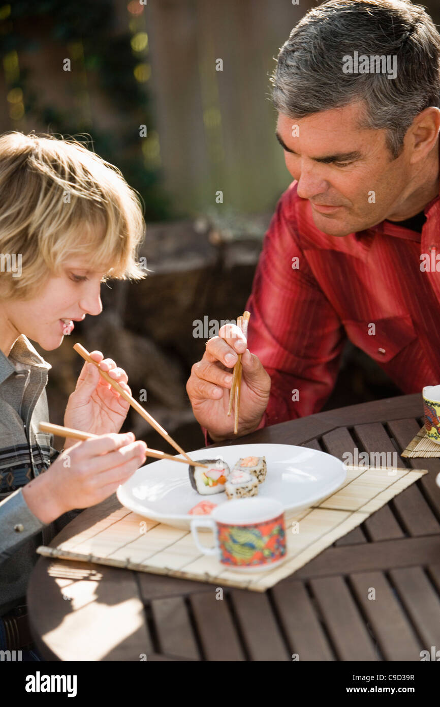 Father showing son how to eat sushi with chopsticks Stock Photo - Alamy