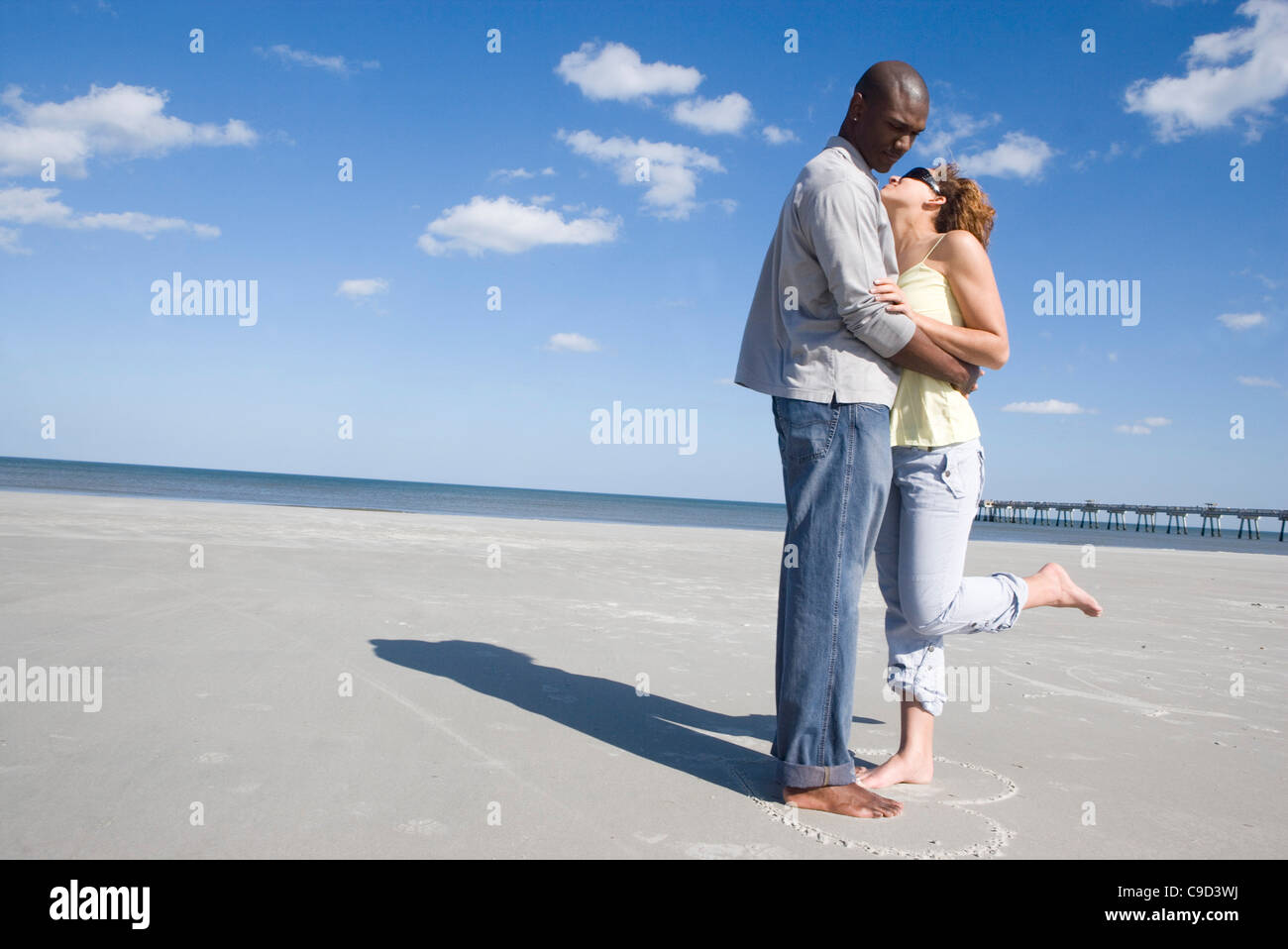 Side view of a romantic young couple embracing on beach Stock Photo - Alamy